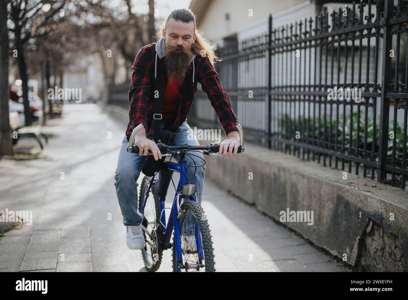 Urban businessman with a beard riding a bicycle on a city street ...