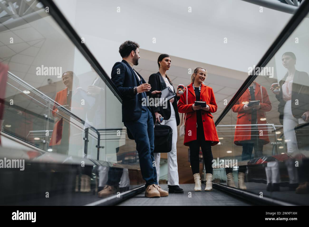 Business colleagues on escalator in modern building discussing work ...
