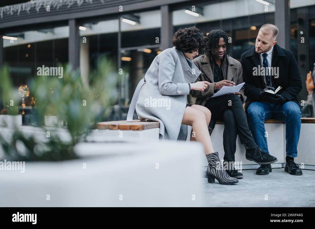 Three people engage in a conversation while reviewing documents. Casual ...