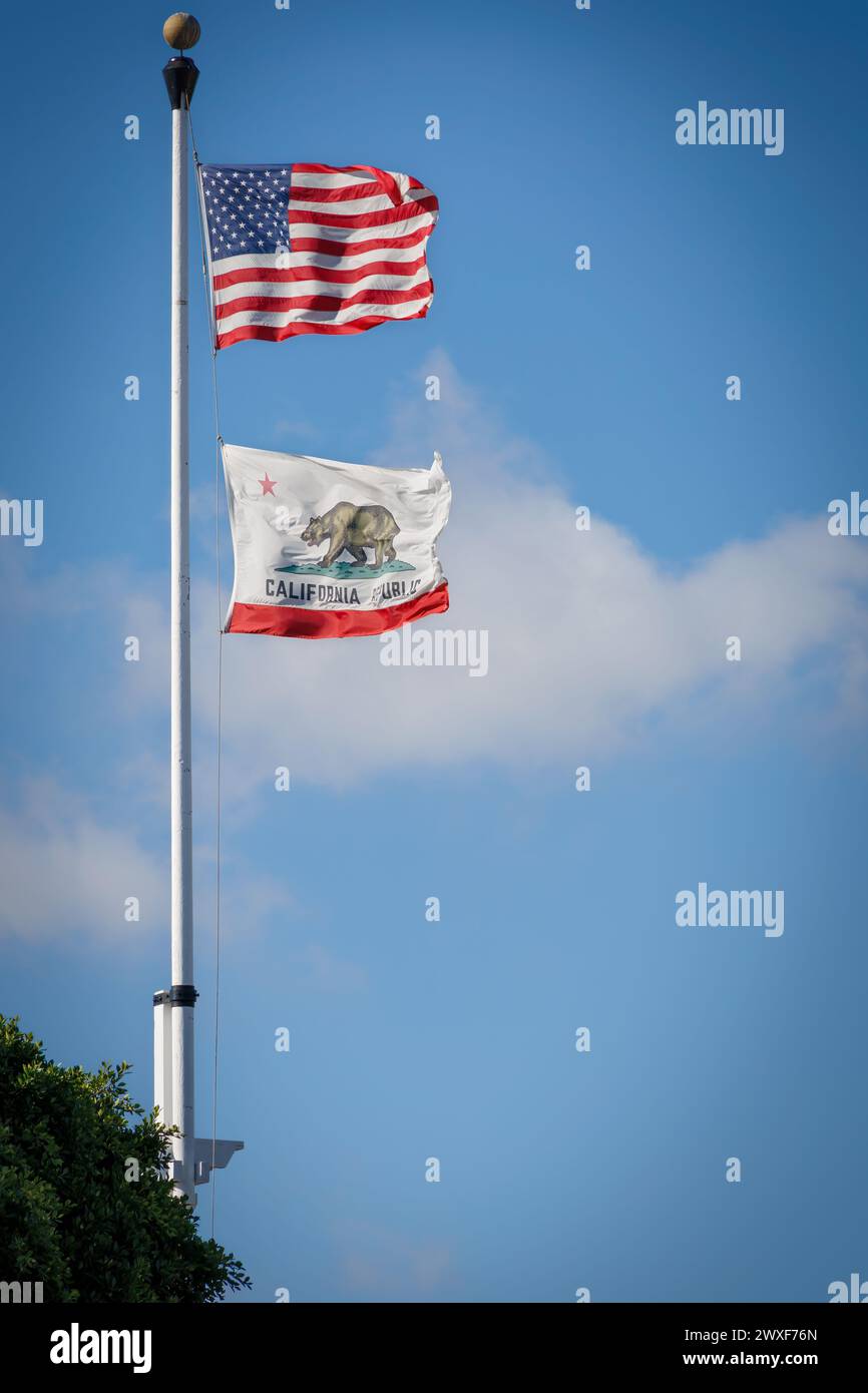 The United States and California State flags fly on a windy day from a ...