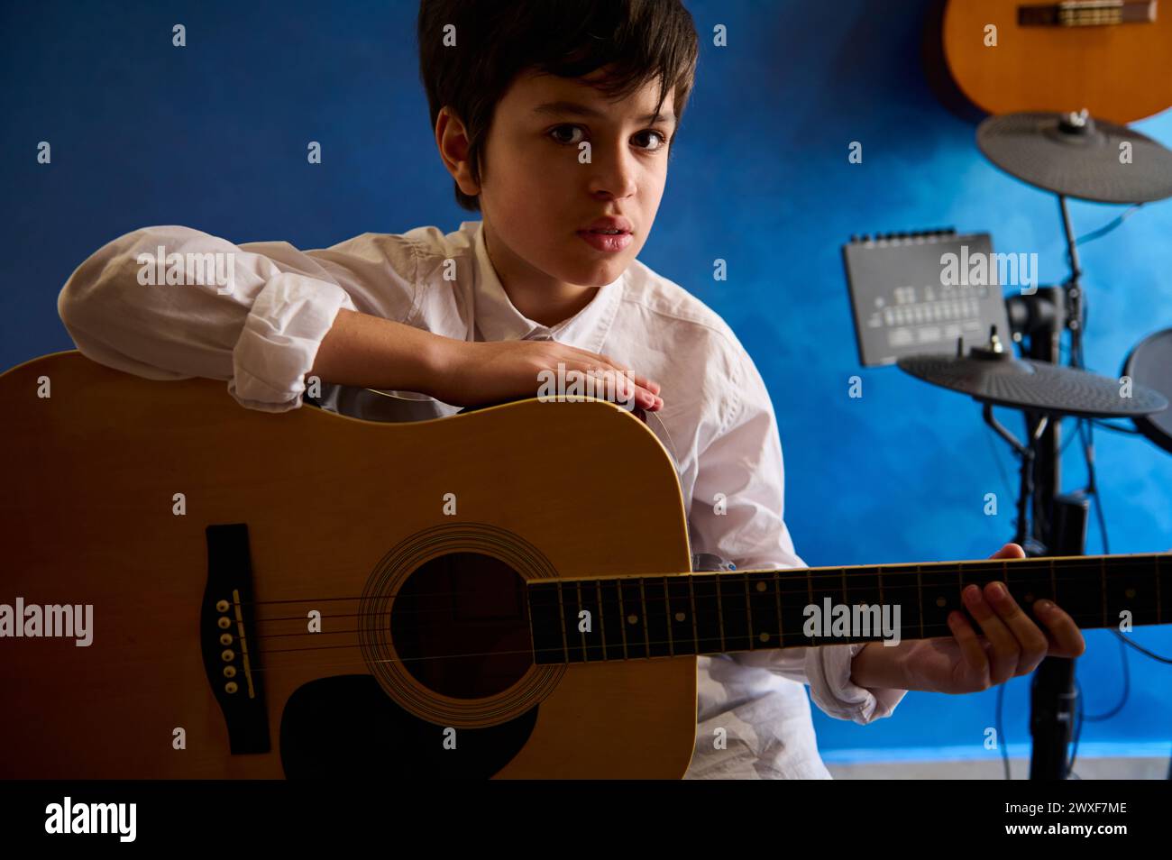 Authentic portrait of handsome teenage boy playing guitar in the modern ...