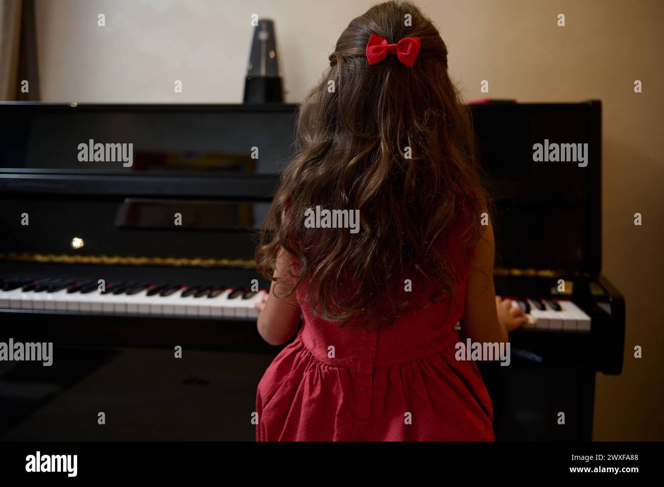 View from the back of a little girl in elegant red dress, sitting at ...