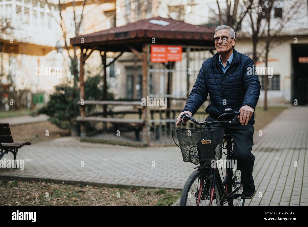 An active elderly man with glasses rides his bike through a serene park ...