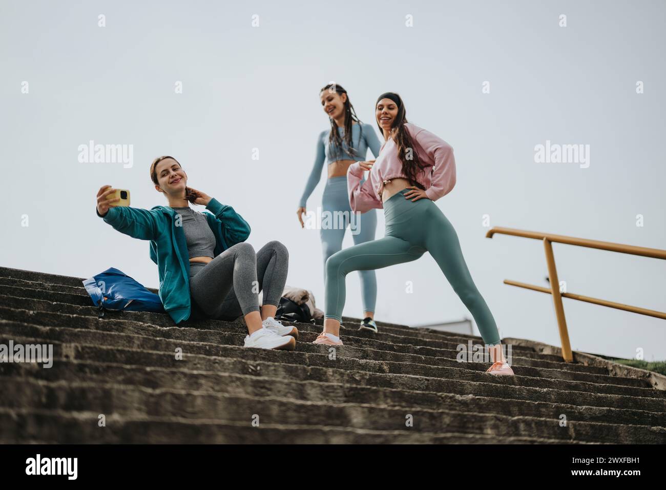 Active women taking a selfie during workout break on outdoor stairs ...