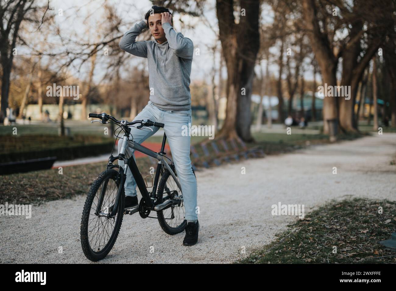 Active man taking a break with his bicycle in a serene park setting ...