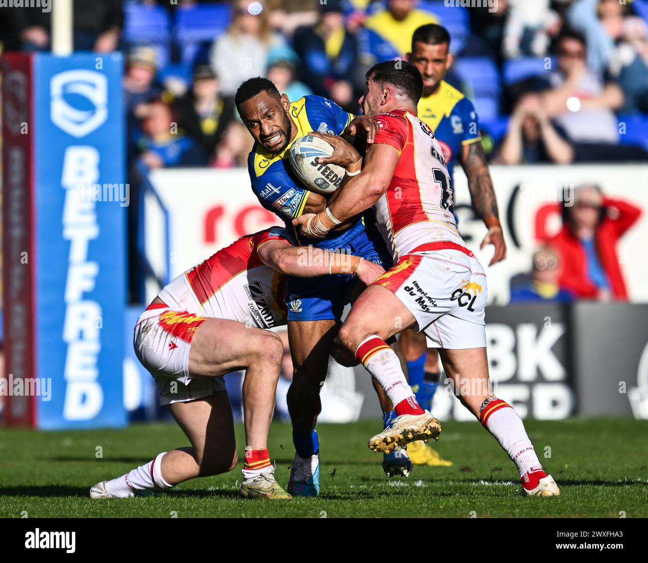 Rodrick Tai of Warrington Wolves is tackled by Tom Davies of Catalan ...