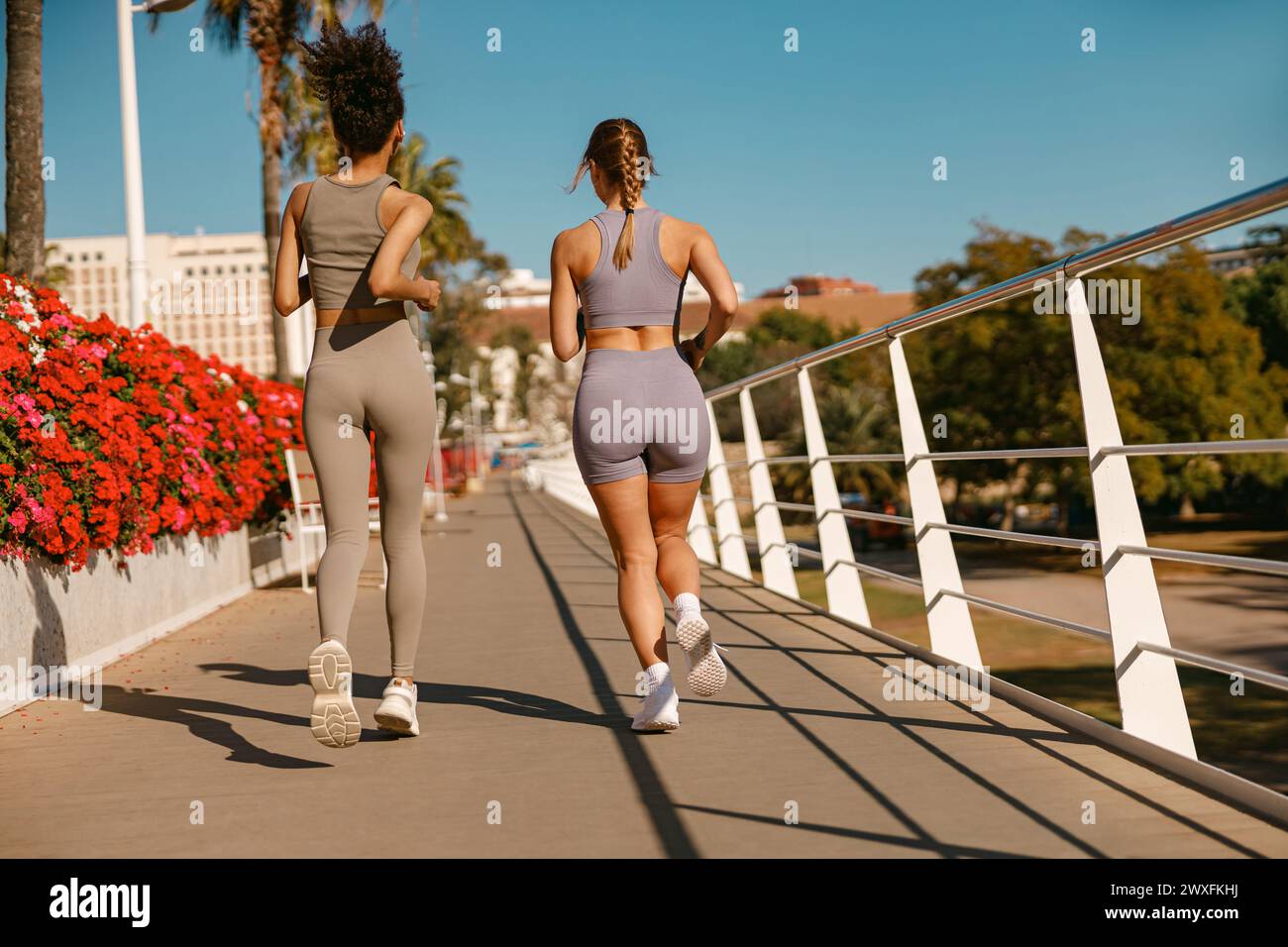 Back view of two women in sportswear are running on buildings ...