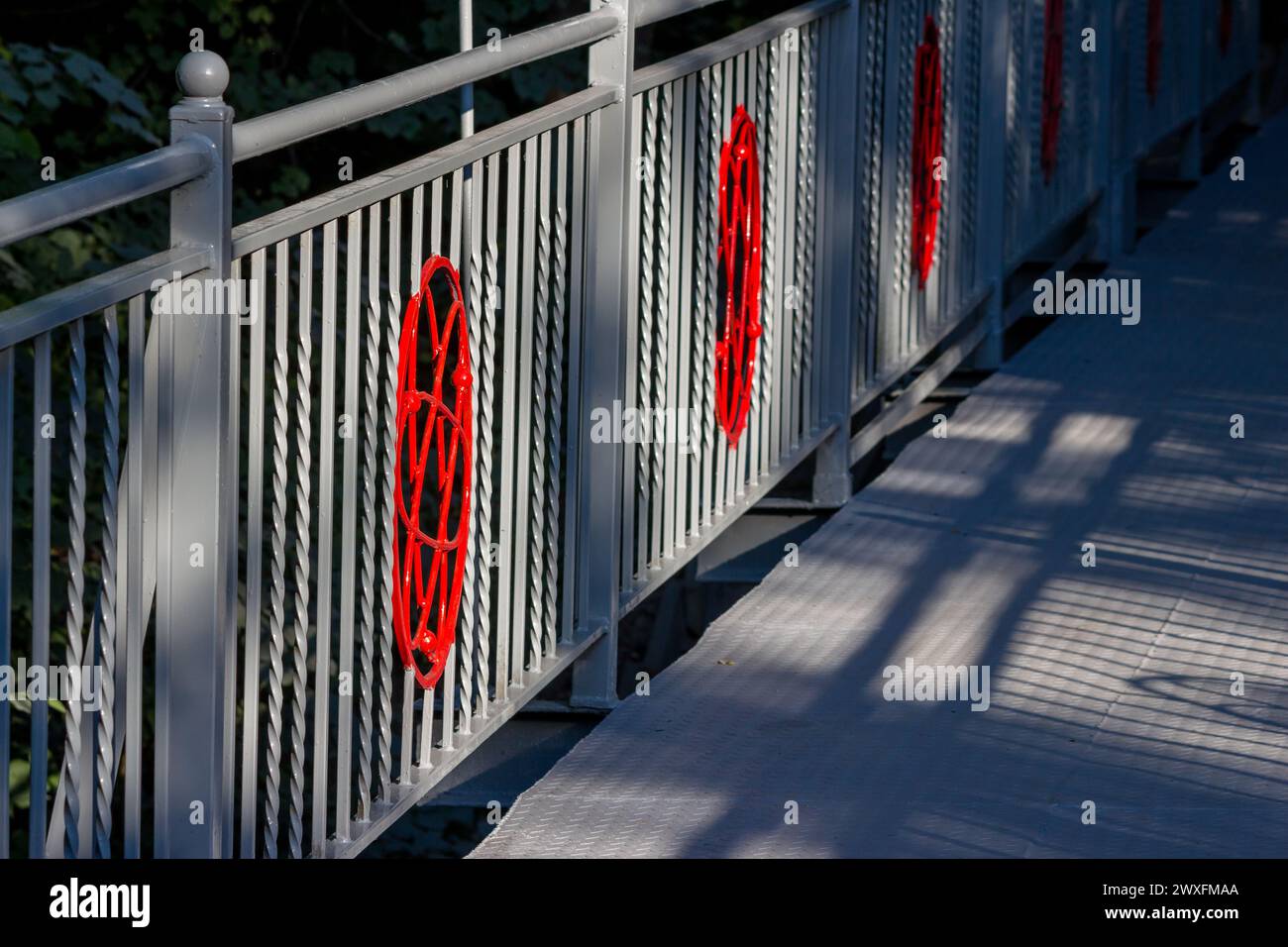 Metal railings of a pedestrian bridge with a bright red atom symbol ...