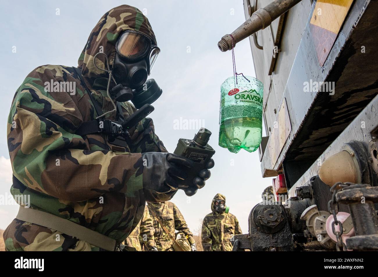 A man in a hazmat suit is holding a bottle of orange juice. He is ...