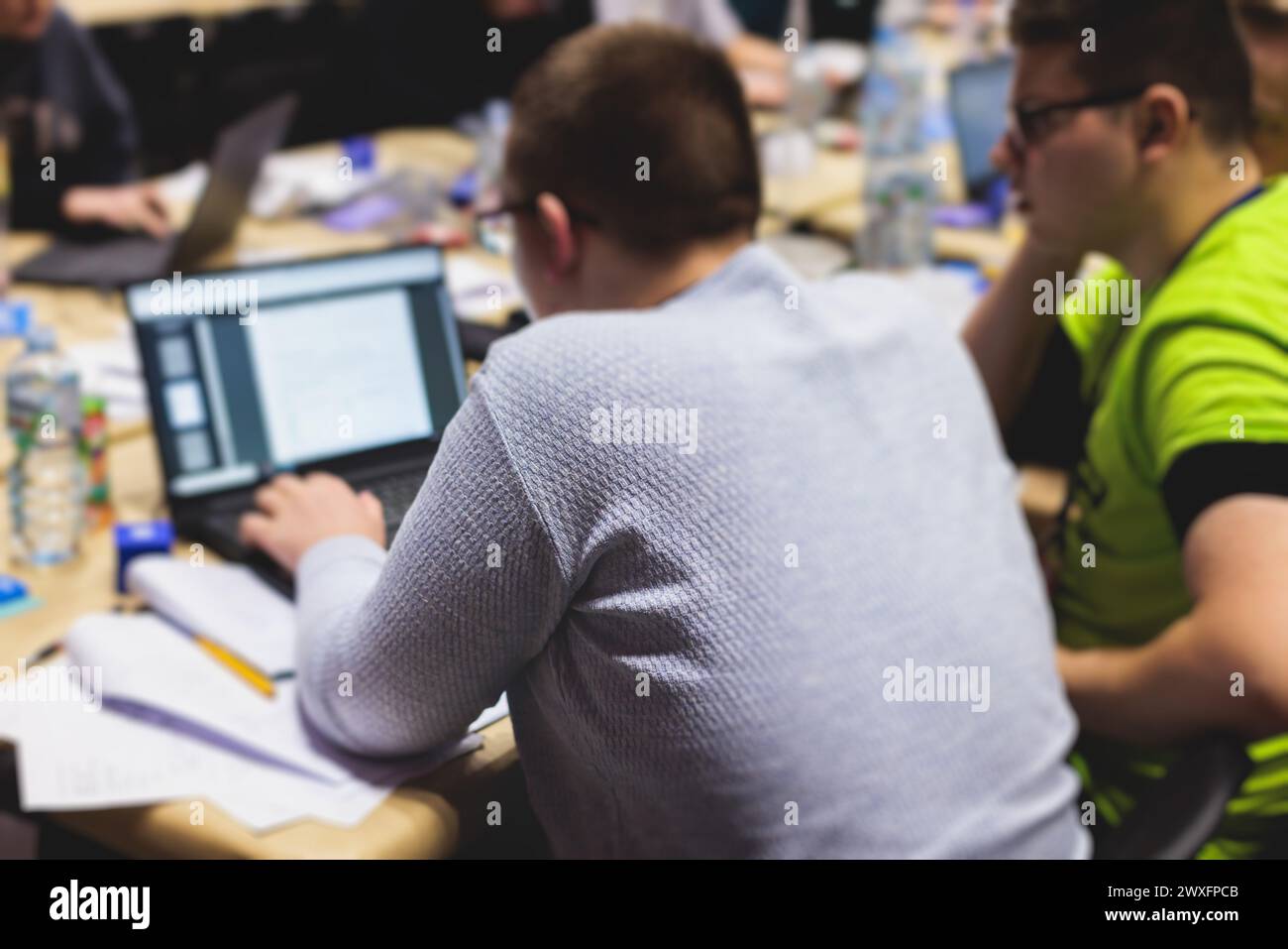 Software developer students in auditorium hall working on computer and ...