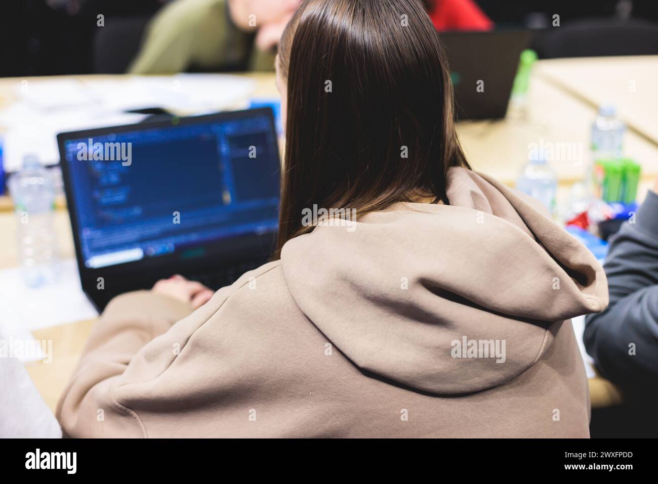 Software developer students in auditorium hall working on computer and laptop, programming ...