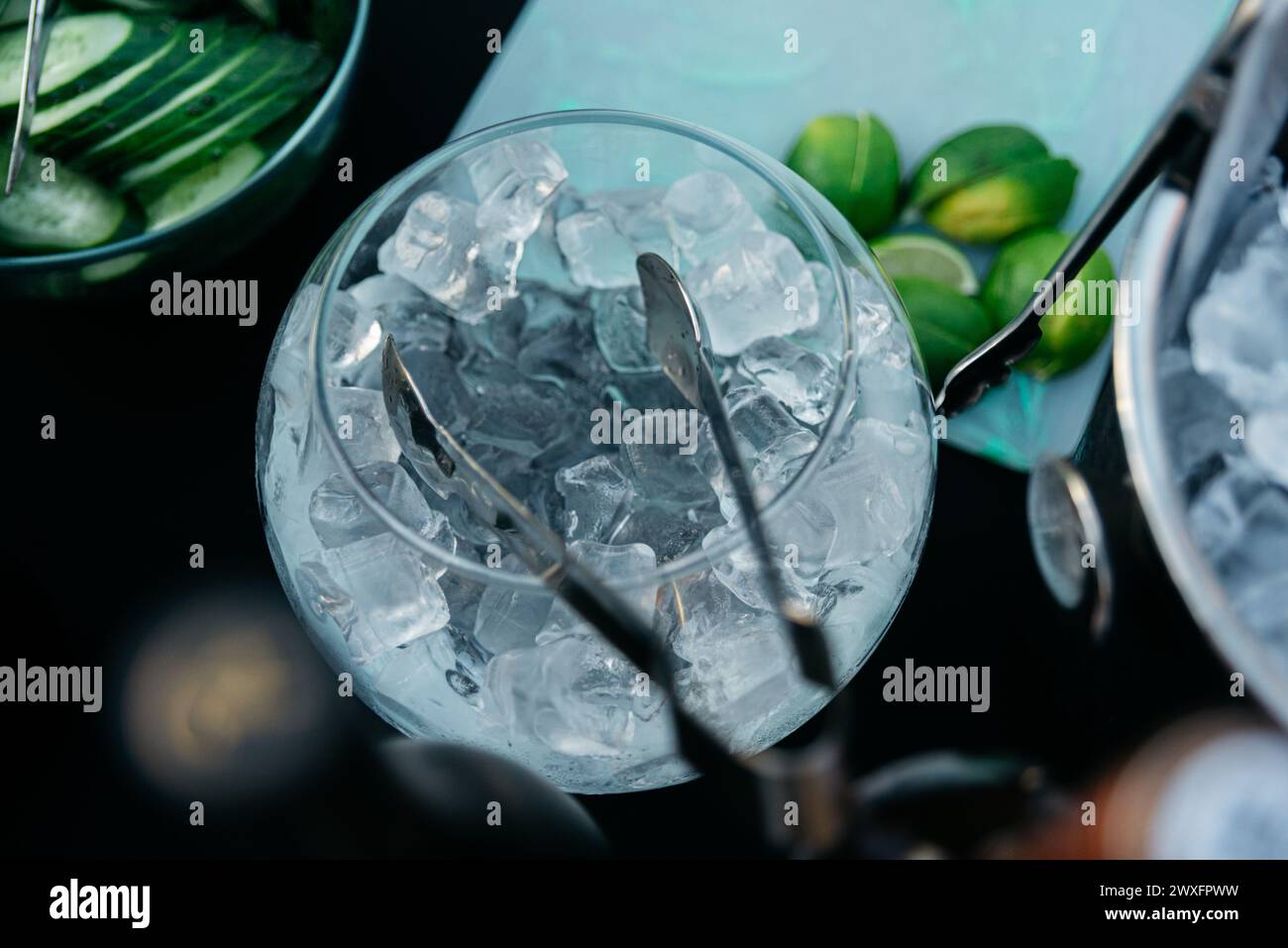 A close-up view of a cocktail being prepared, with ice cubes and a bar ...