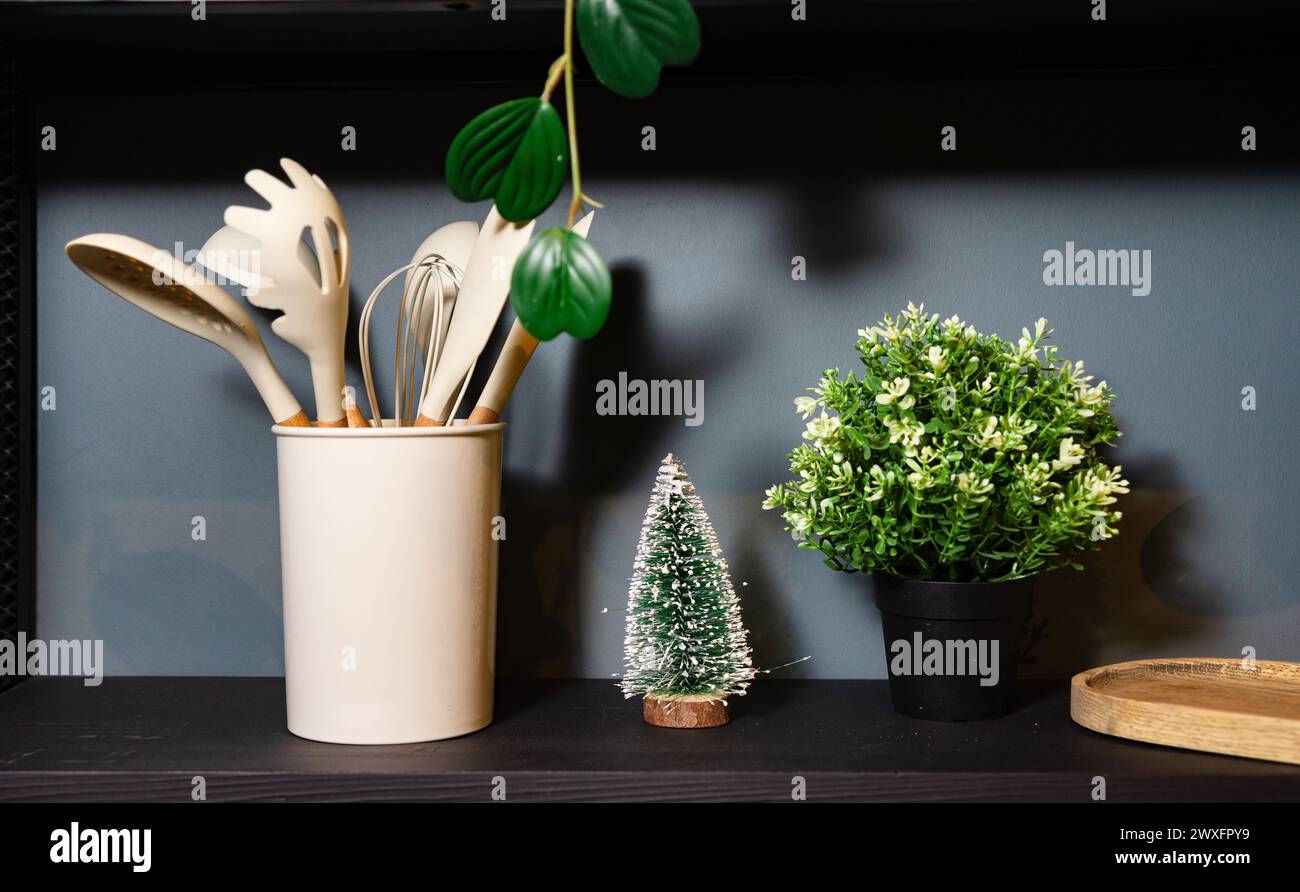 Modern kitchen utensils in a holder next to a miniature Christmas tree ...