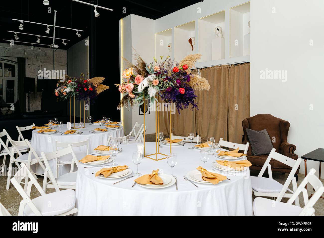 A sophisticated event space featuring round tables with white linens ...
