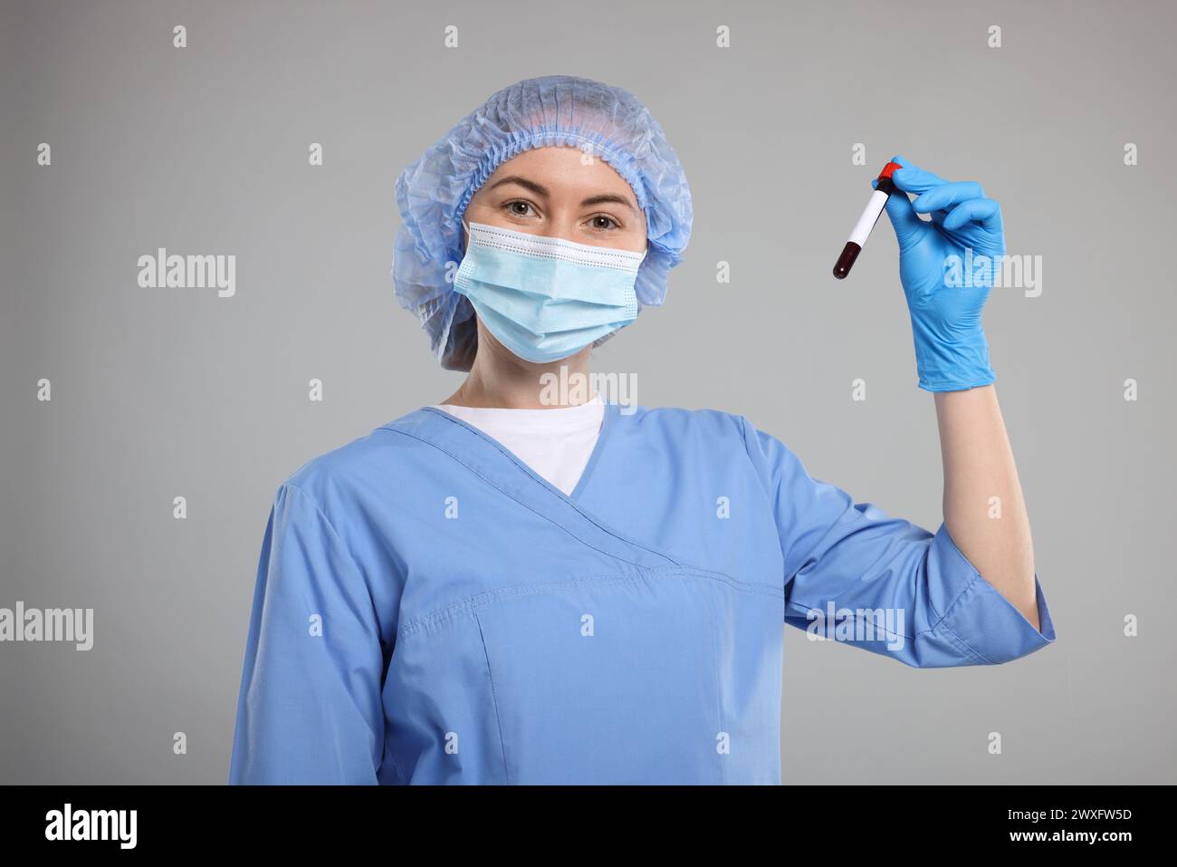 Laboratory testing. Doctor with blood sample in tube on light grey ...