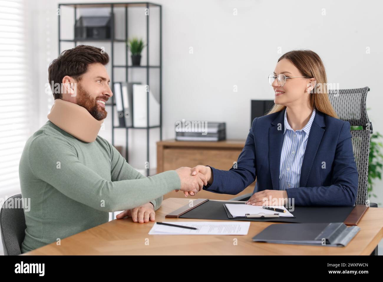 Lawyer shaking hands with injured client in office Stock Photo - Alamy
