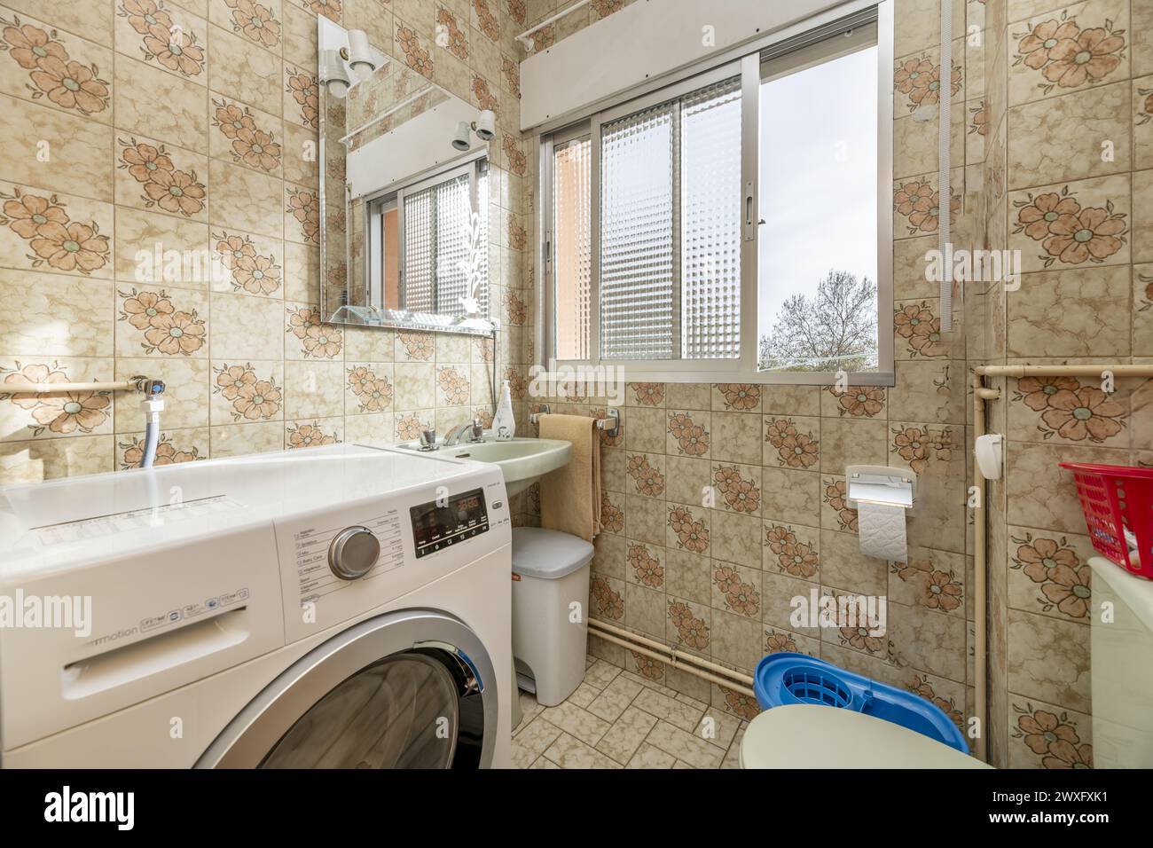 Small bathroom with a washing machine, old ugly tiles, beveled mirror ...