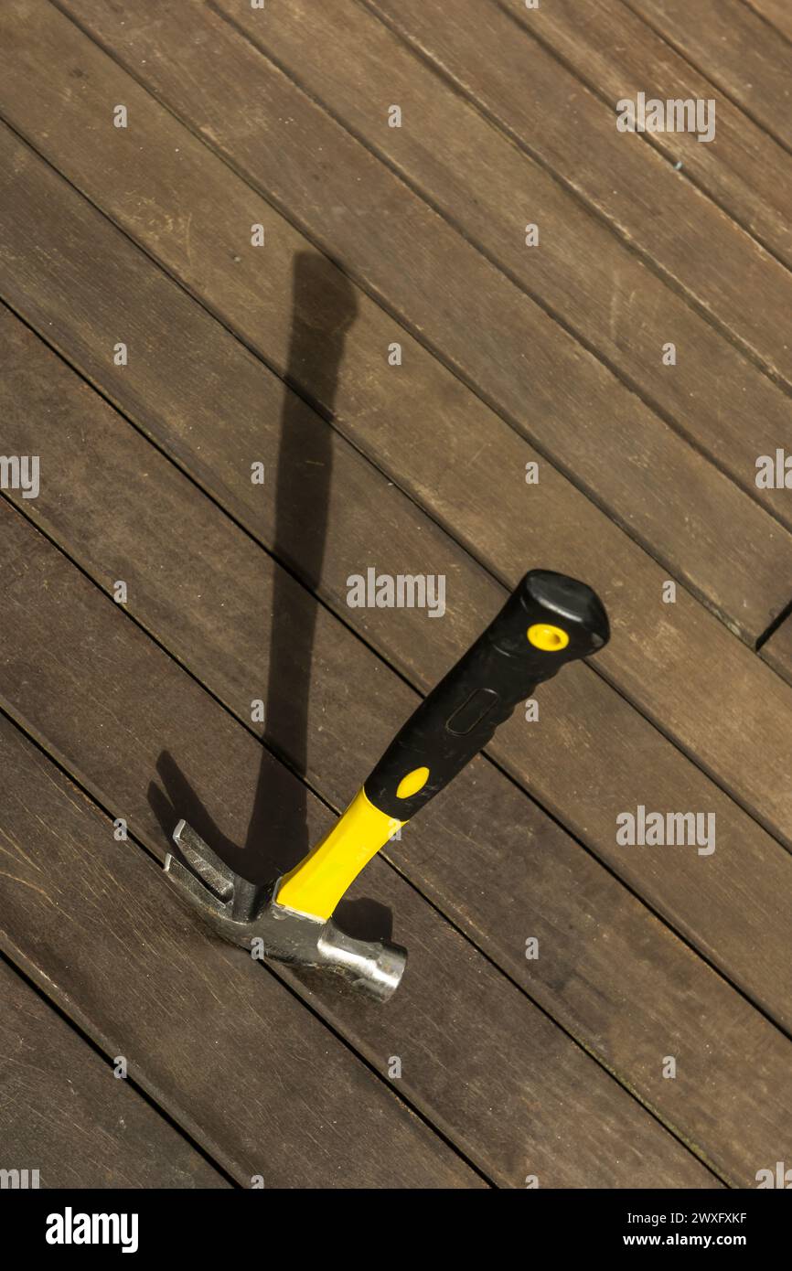 A multi-purpose hammer with a yellow and black handle resting on its ...