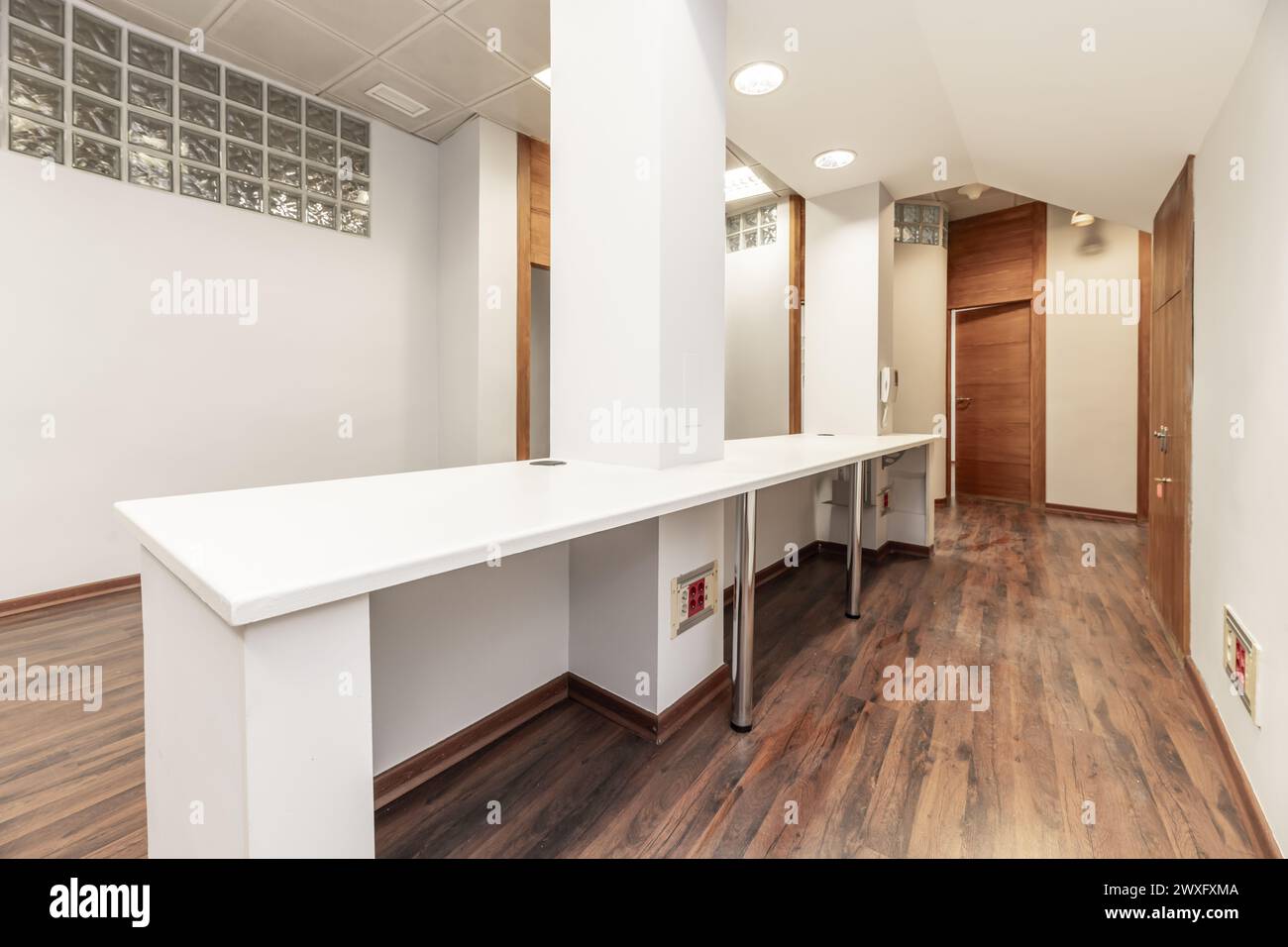 White wooden central counter with cylindrical metal posts and skylights ...