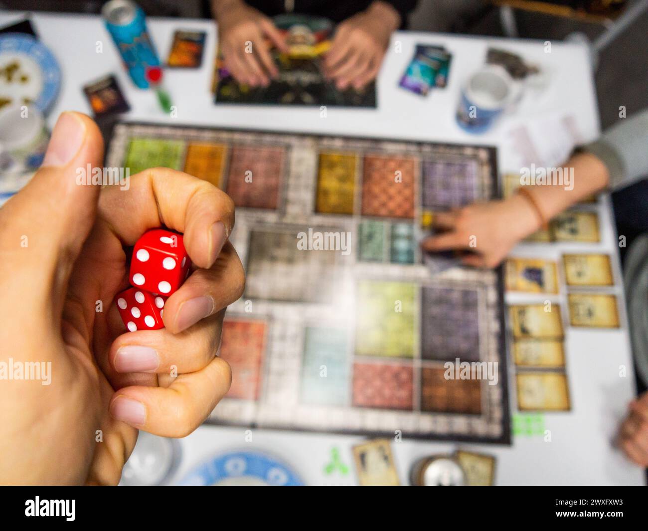 Hand with red six-sided dice on game board from above with other real ...