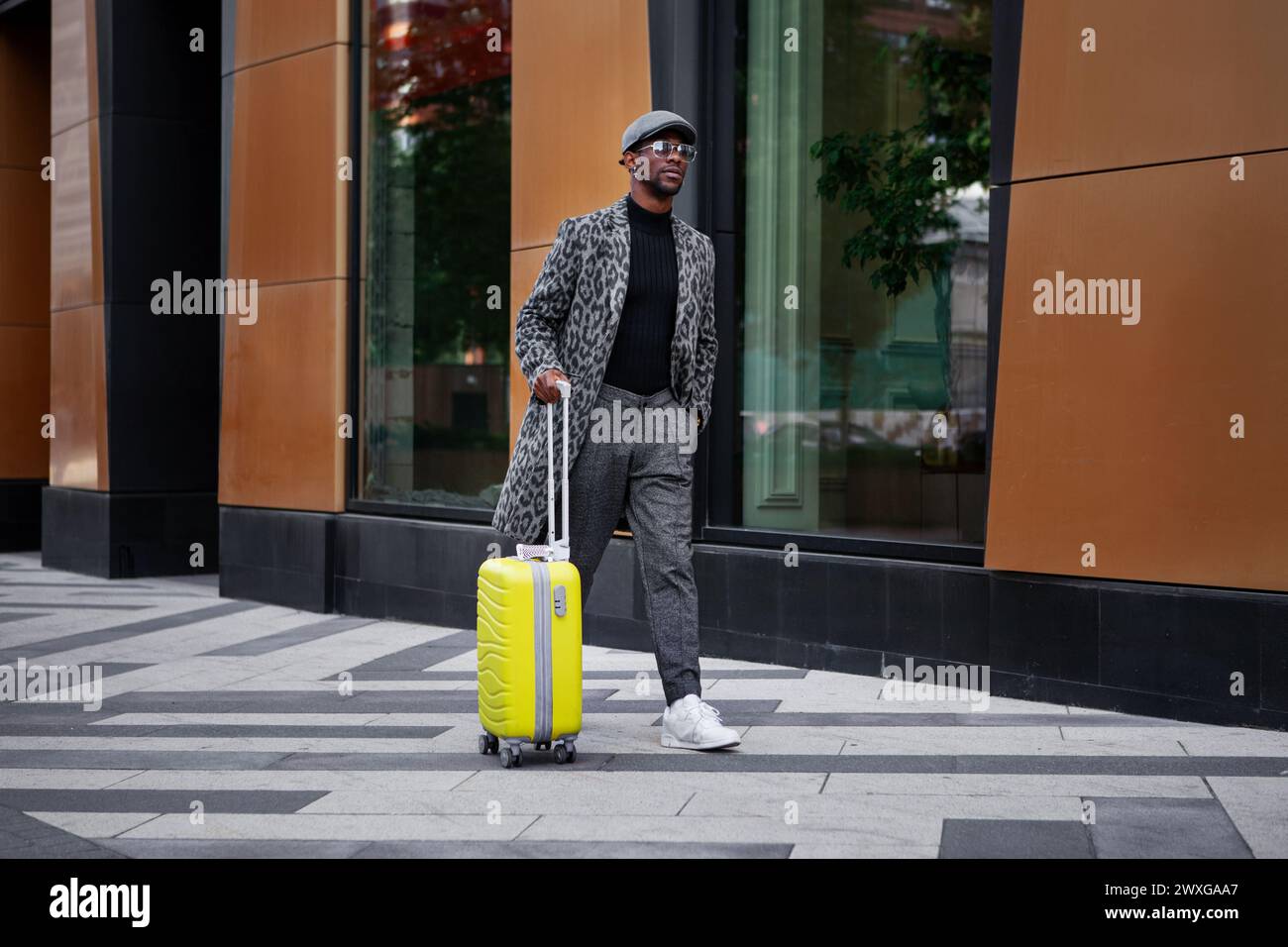 Stylishly dressed male model walks down city street with yellow ...