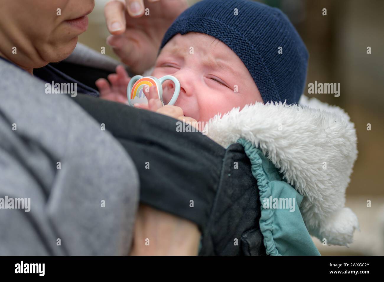 Close up of a screaming and crying baby and the mother is trying to ...