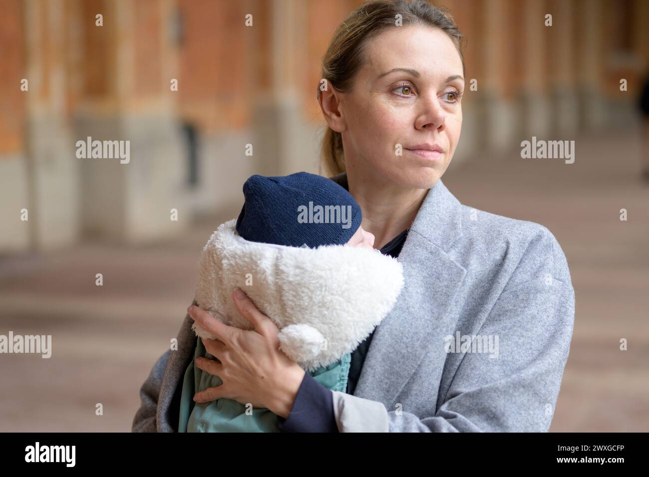 Happy late-term mother in her 40s holding her newborn baby and looking ...