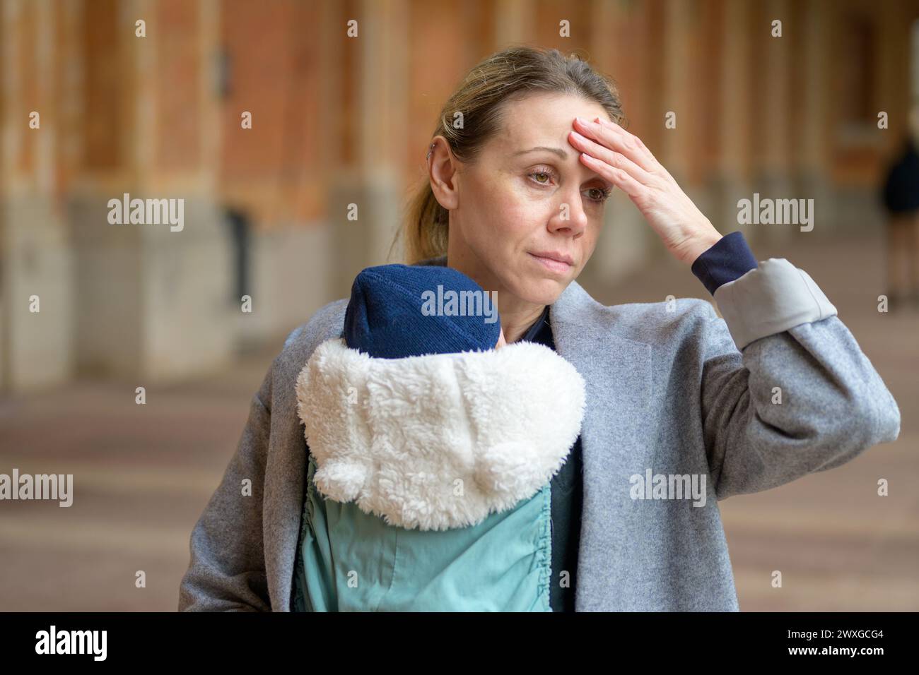 Exhausted and stressed late-term mother in her 40s holding her newborn ...
