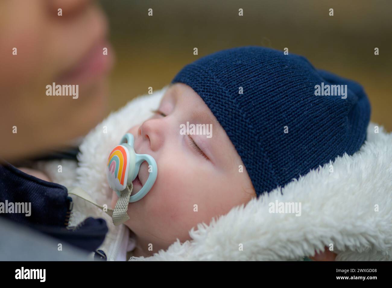 Extreme close up of little baby sleeping with a pacifier and a blue hat ...