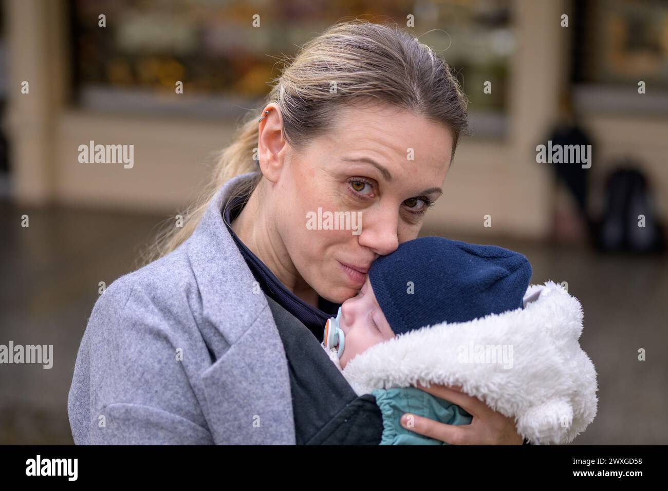 Exhausted happy mother in her 40s holding her newborn baby in a baby ...