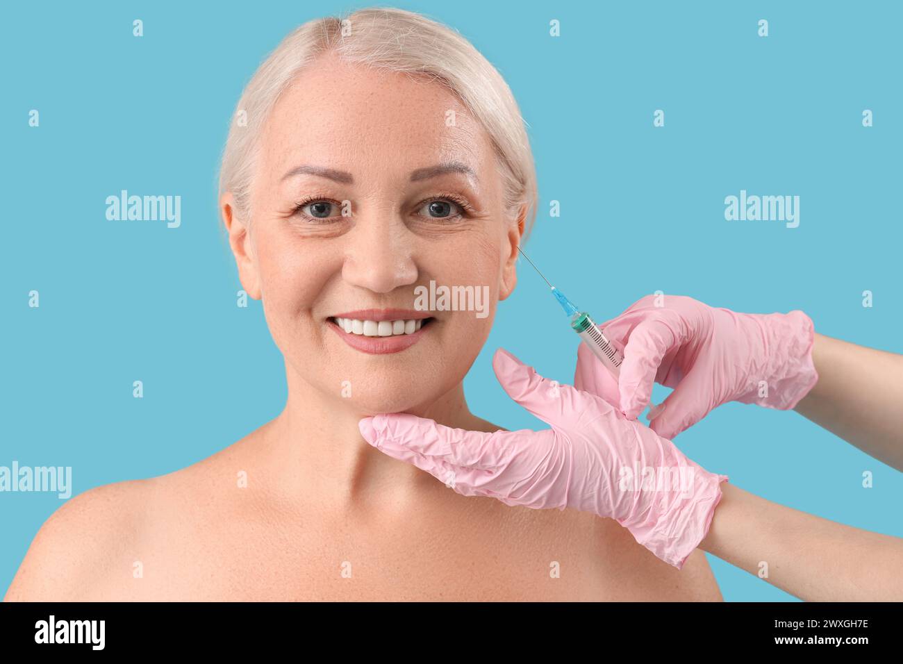 Beautiful mature woman receiving injection on blue background, closeup ...