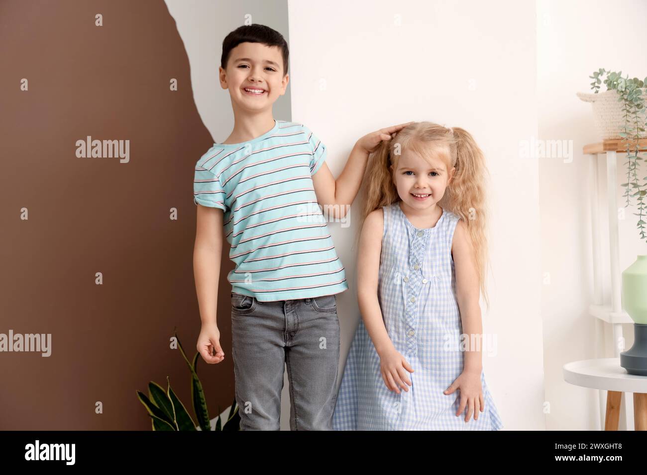 Cute little kids measuring height near wall Stock Photo - Alamy