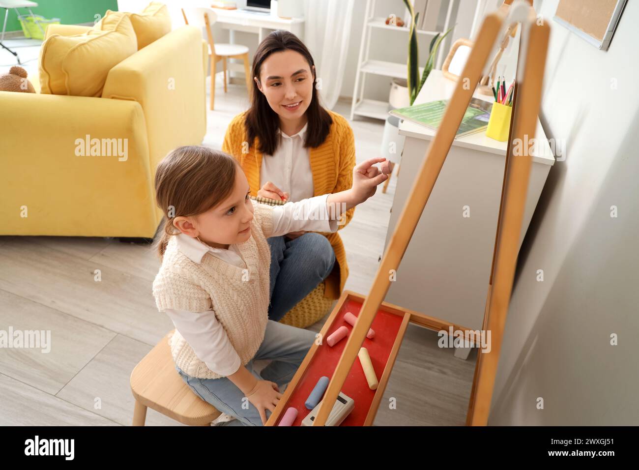 Little girl with psychologist drawing on chalkboard in office Stock ...