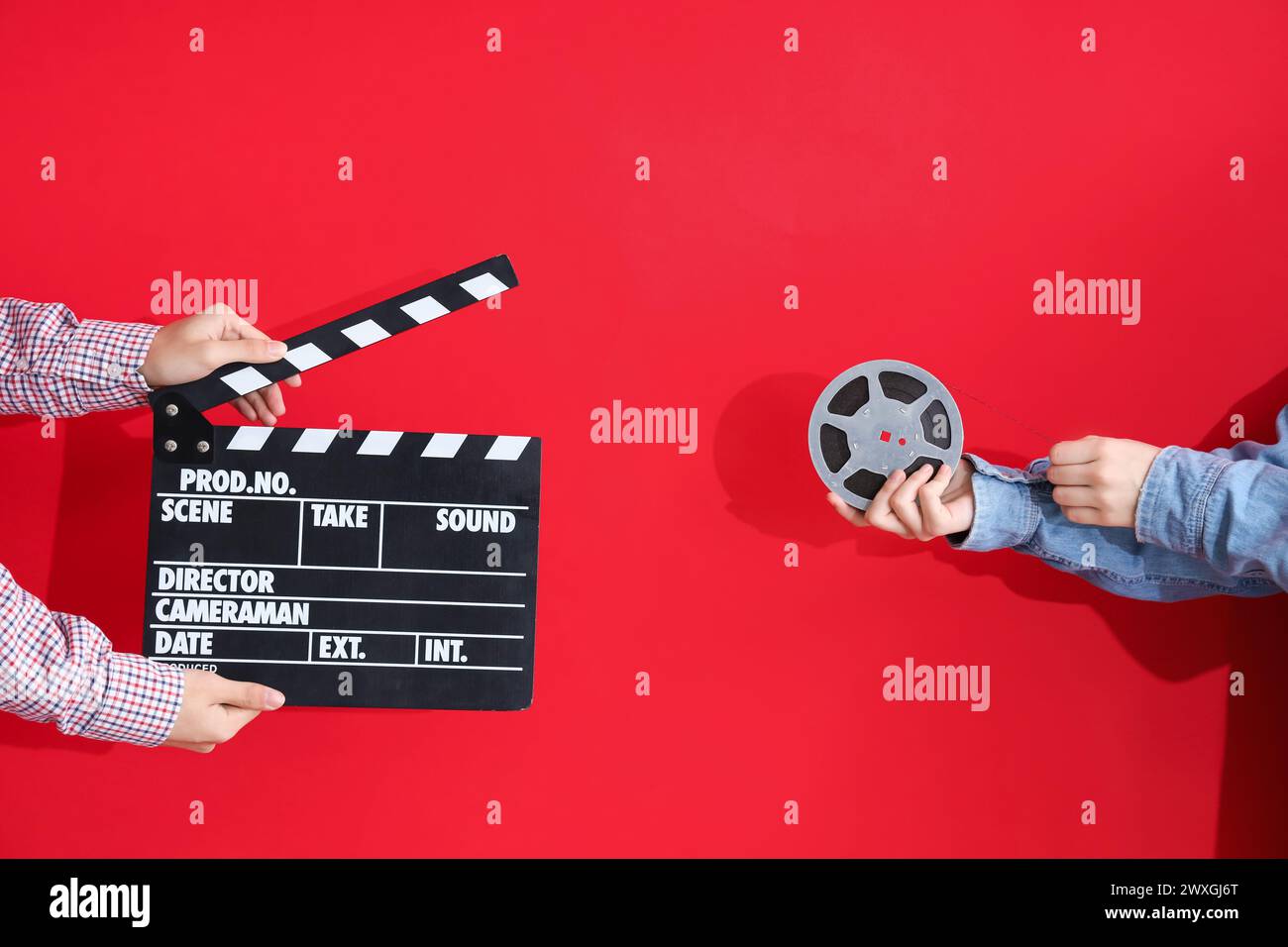 Hands with movie clapper and film reel on red background Stock Photo ...