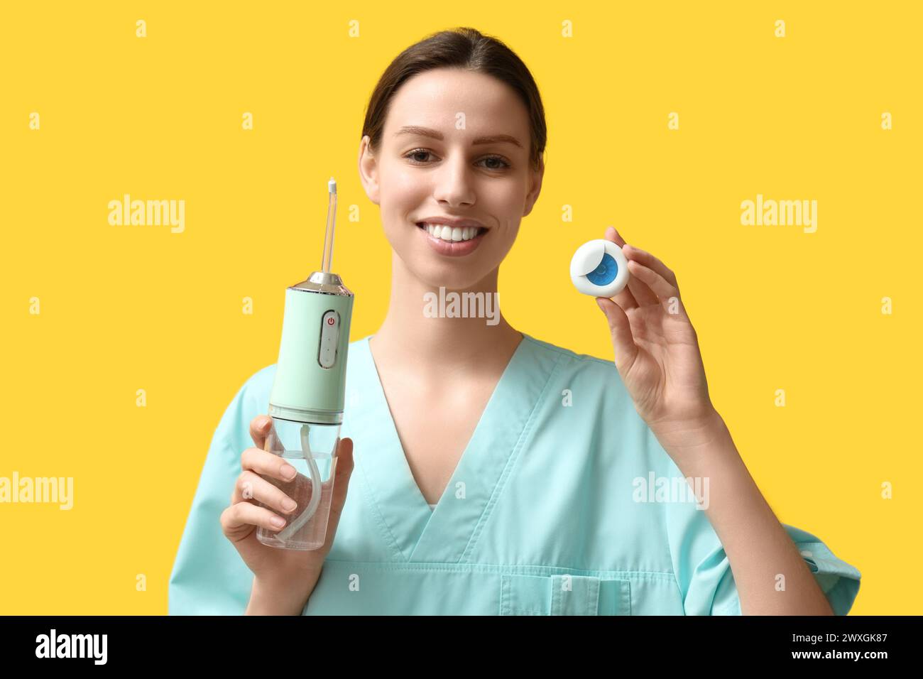 Female dentist with oral irrigator and dental floss on yellow ...