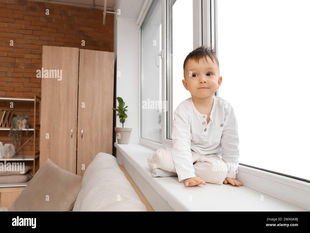 Little boy sitting on windowsill at home. Child in danger Stock Photo ...
