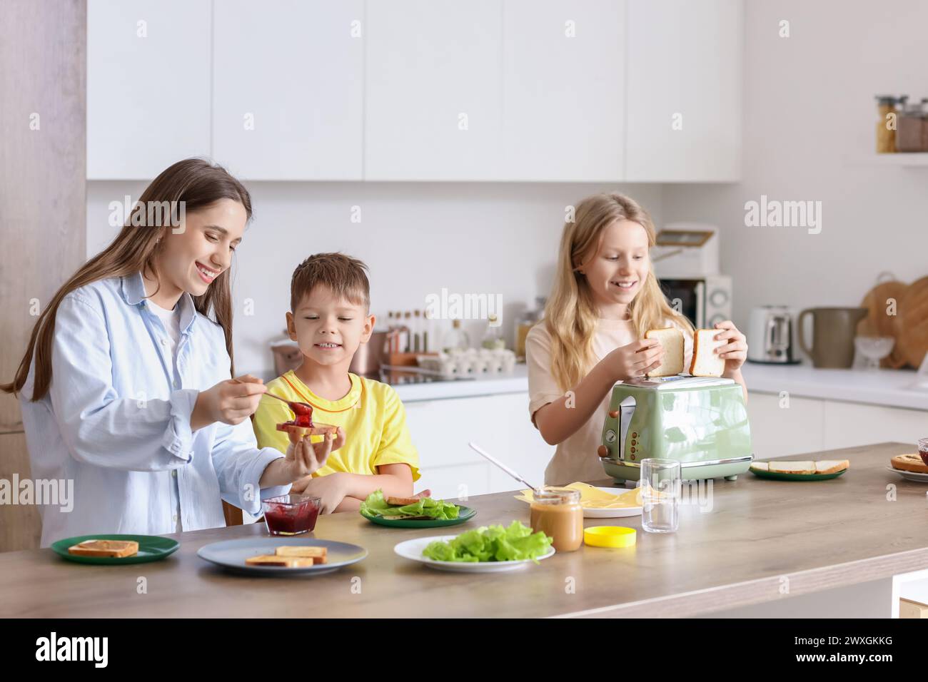 Little children and their mother making toasts in kitchen Stock Photo ...