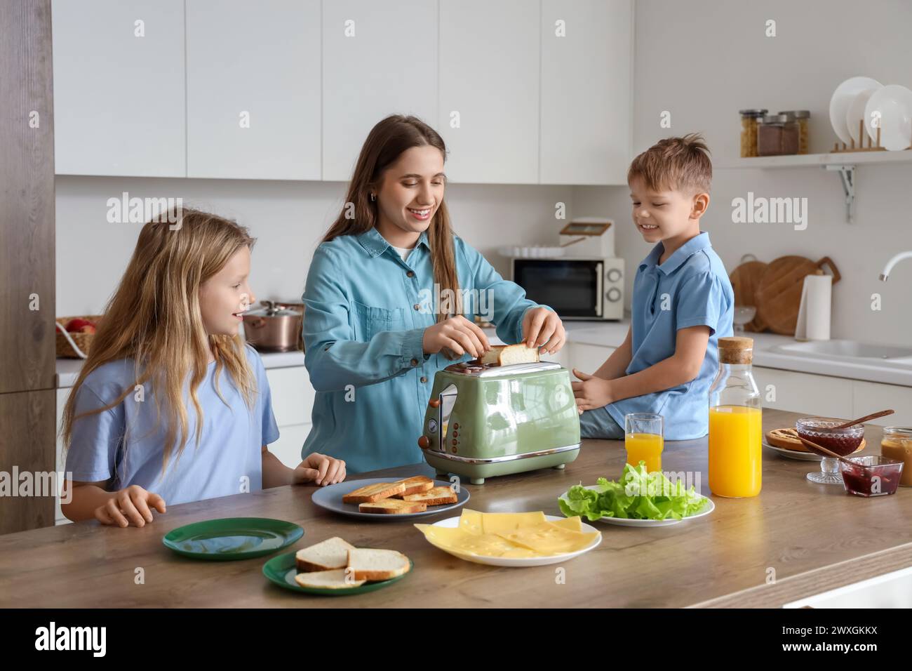 Little children and their mother making toasts in kitchen Stock Photo ...