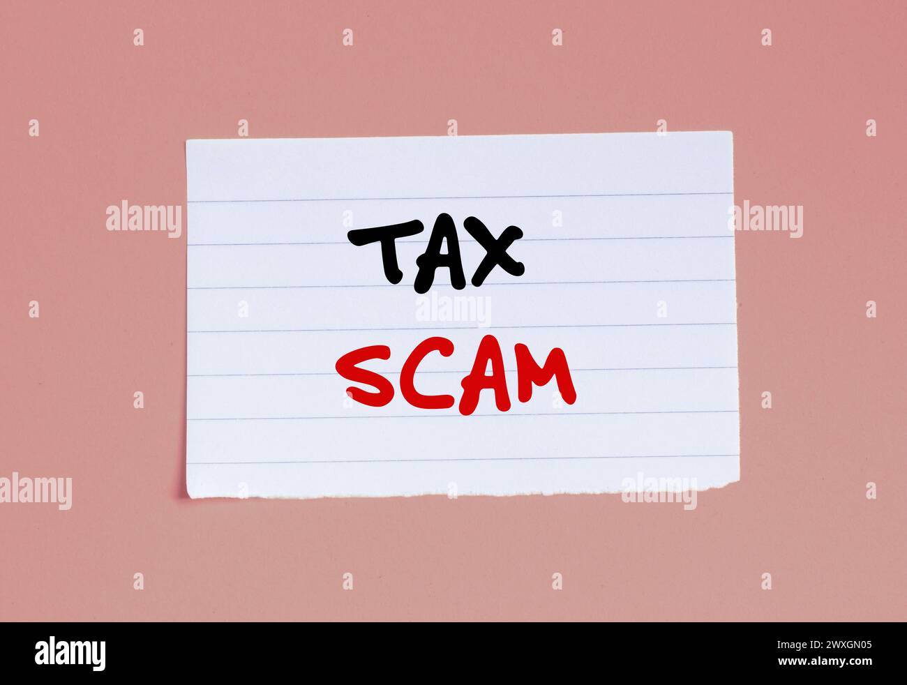 Tax scam words written on torn paper piece with color background ...