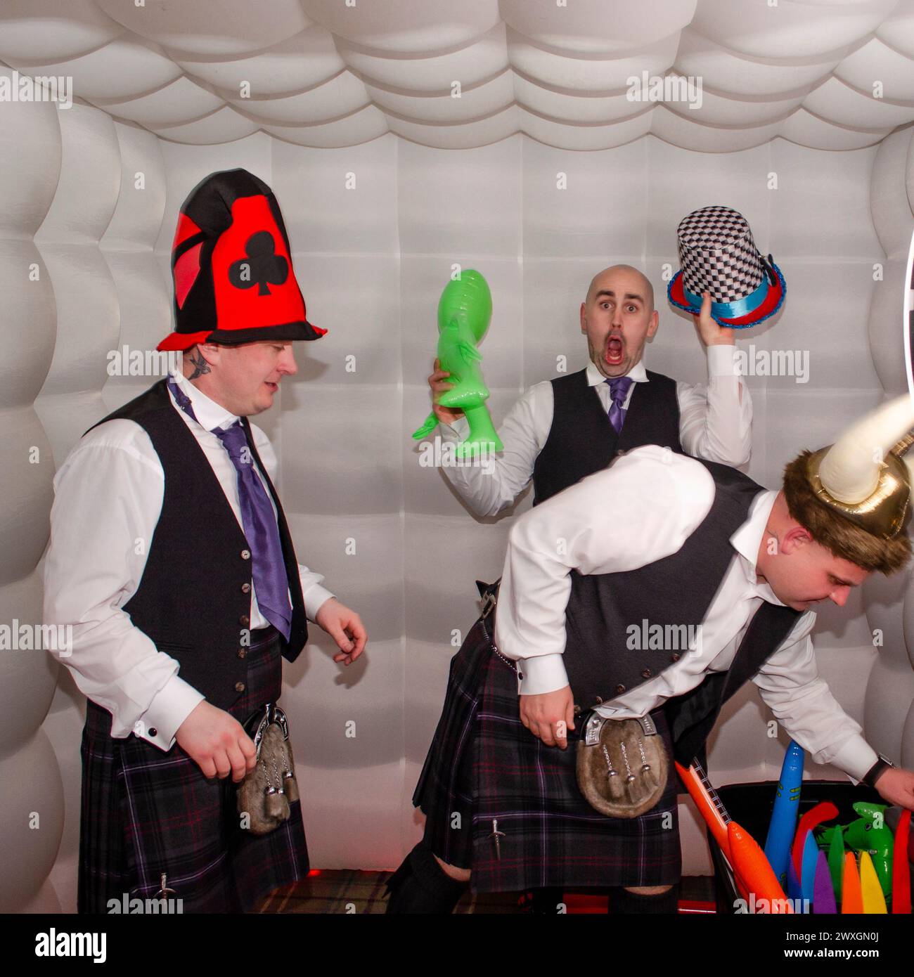 Group of people in a photo booth wearing colourful props, hats, and ...