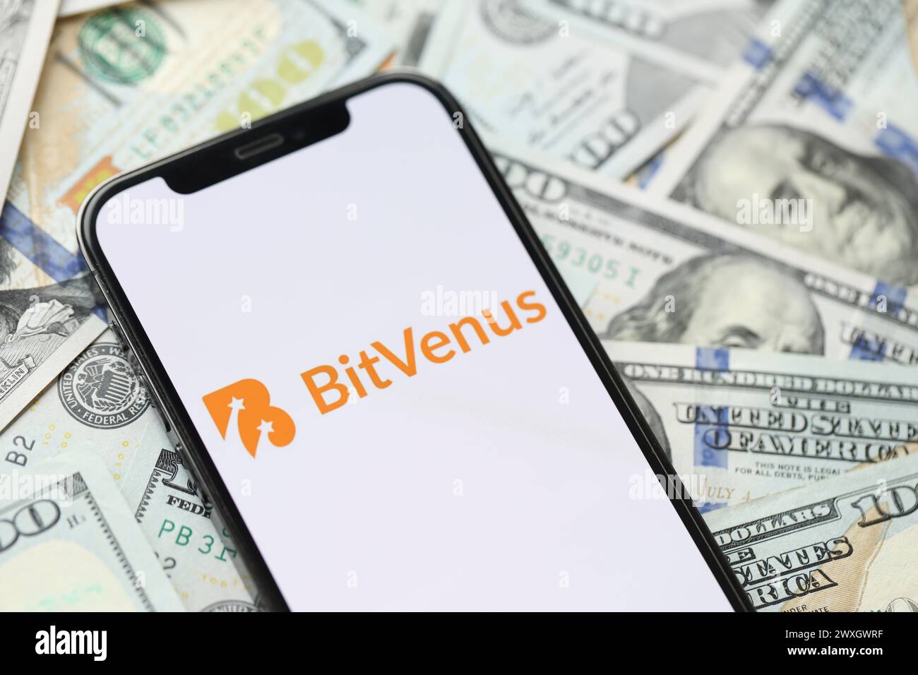 KYIV, UKRAINE - MARCH 15, 2024 Bitvenus logo on iPhone display screen with many hundred dollar ...