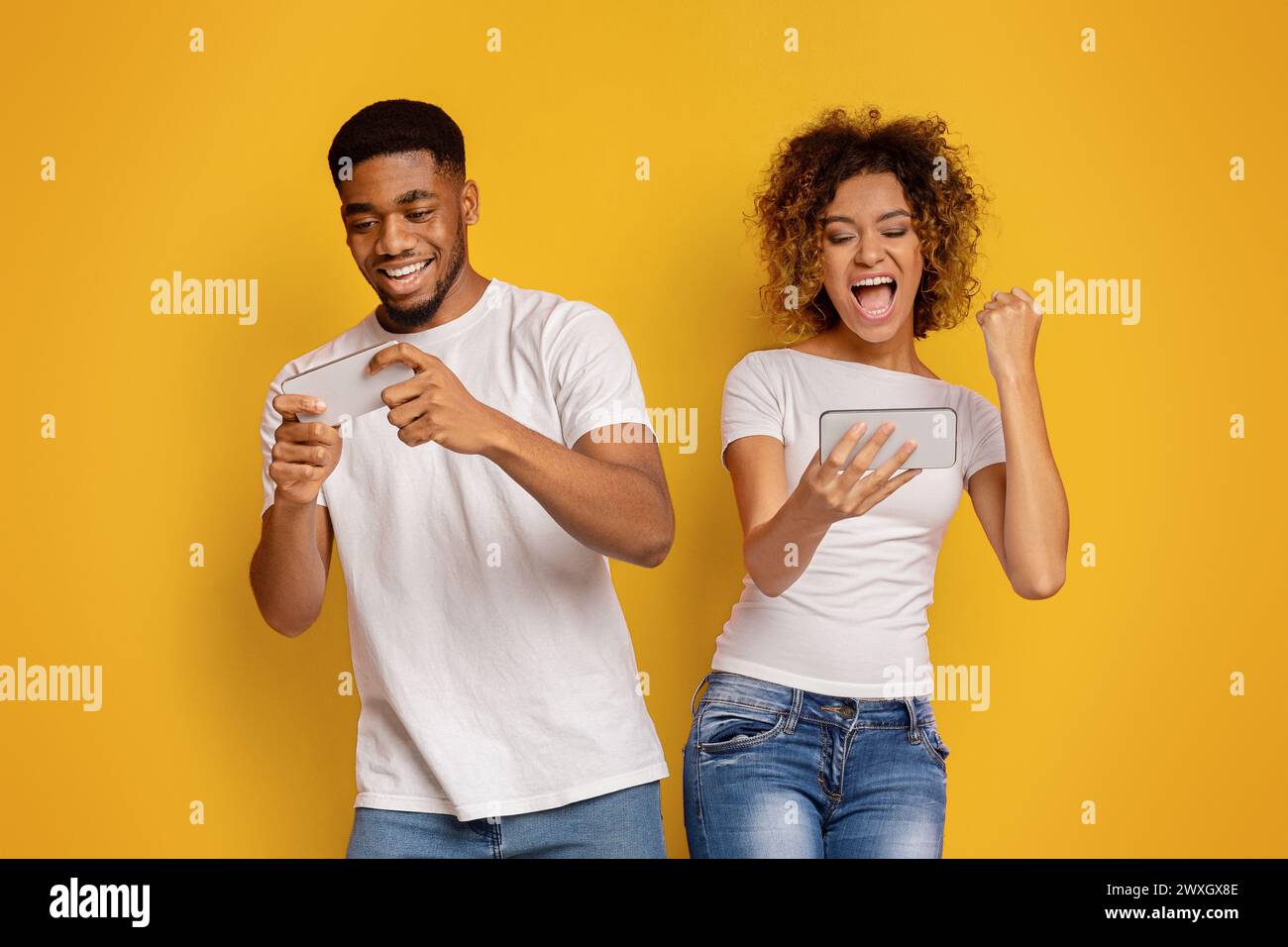 Two people playing games on smartphones on yellow background Stock ...