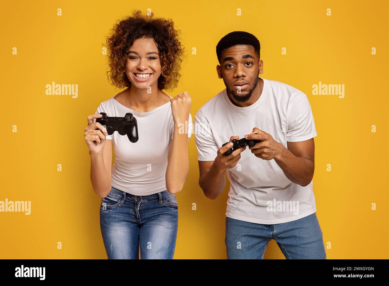 Gaming couple showing enthusiasm and fun on yellow background Stock ...