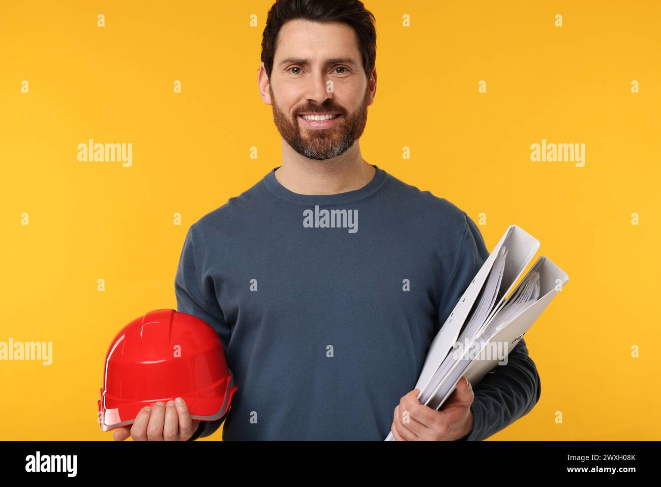 Architect with hard hat and folders on orange background Stock Photo ...