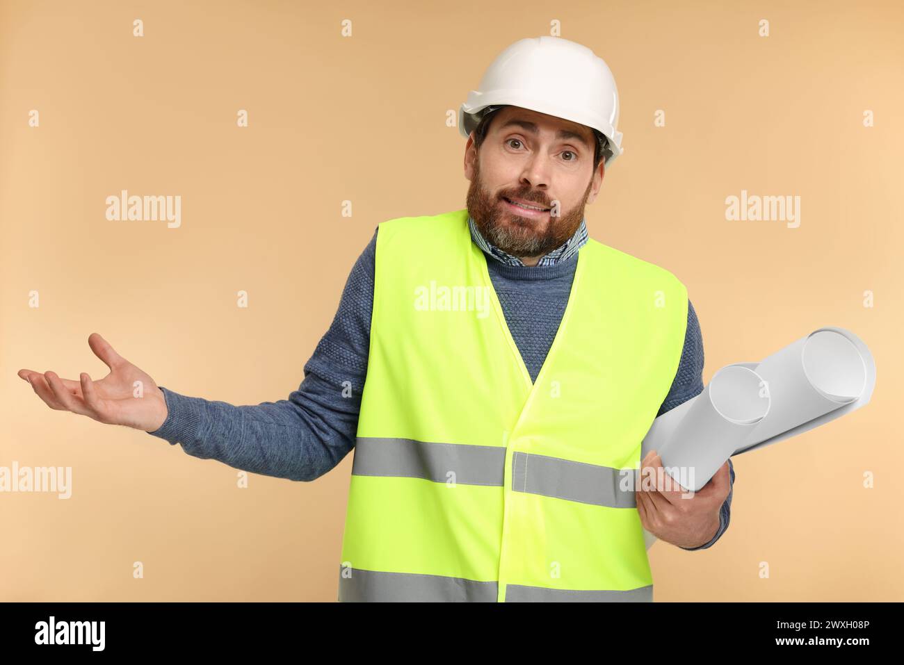 Confused architect in hard hat with drafts on beige background Stock ...