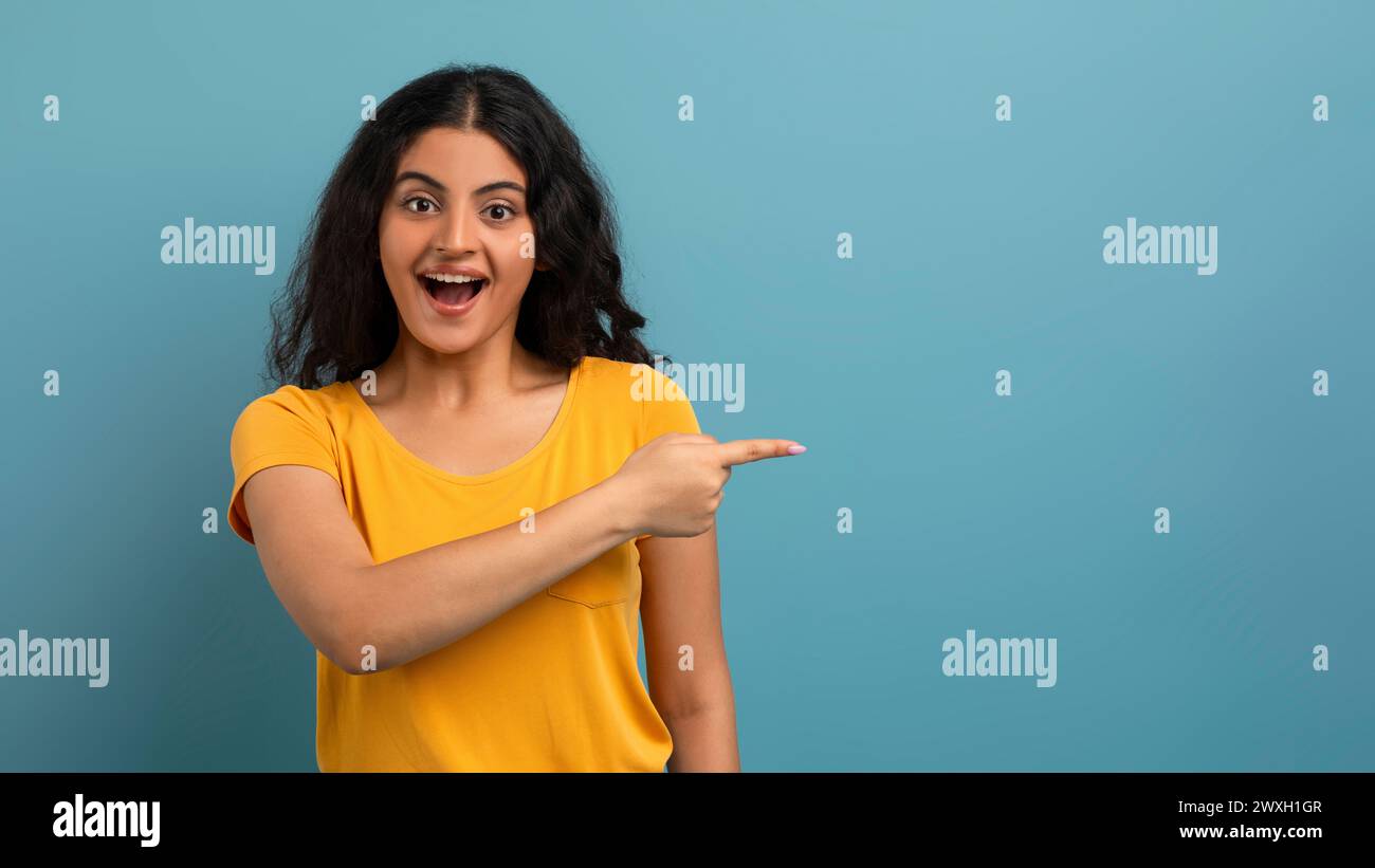 Excited woman pointing outside of frame Stock Photo - Alamy