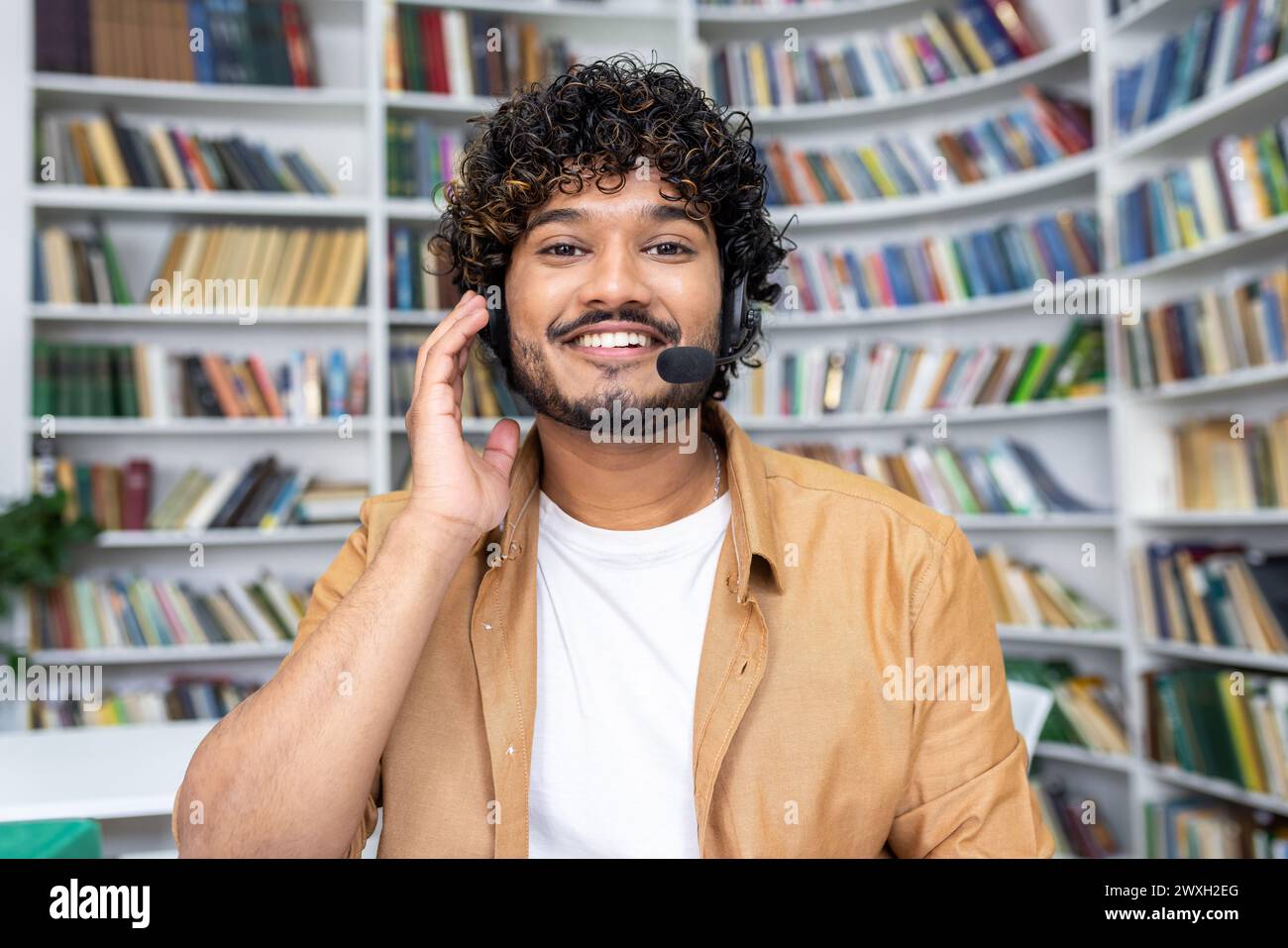 A cheerful young man wearing a headset and smiling as he looks at the ...