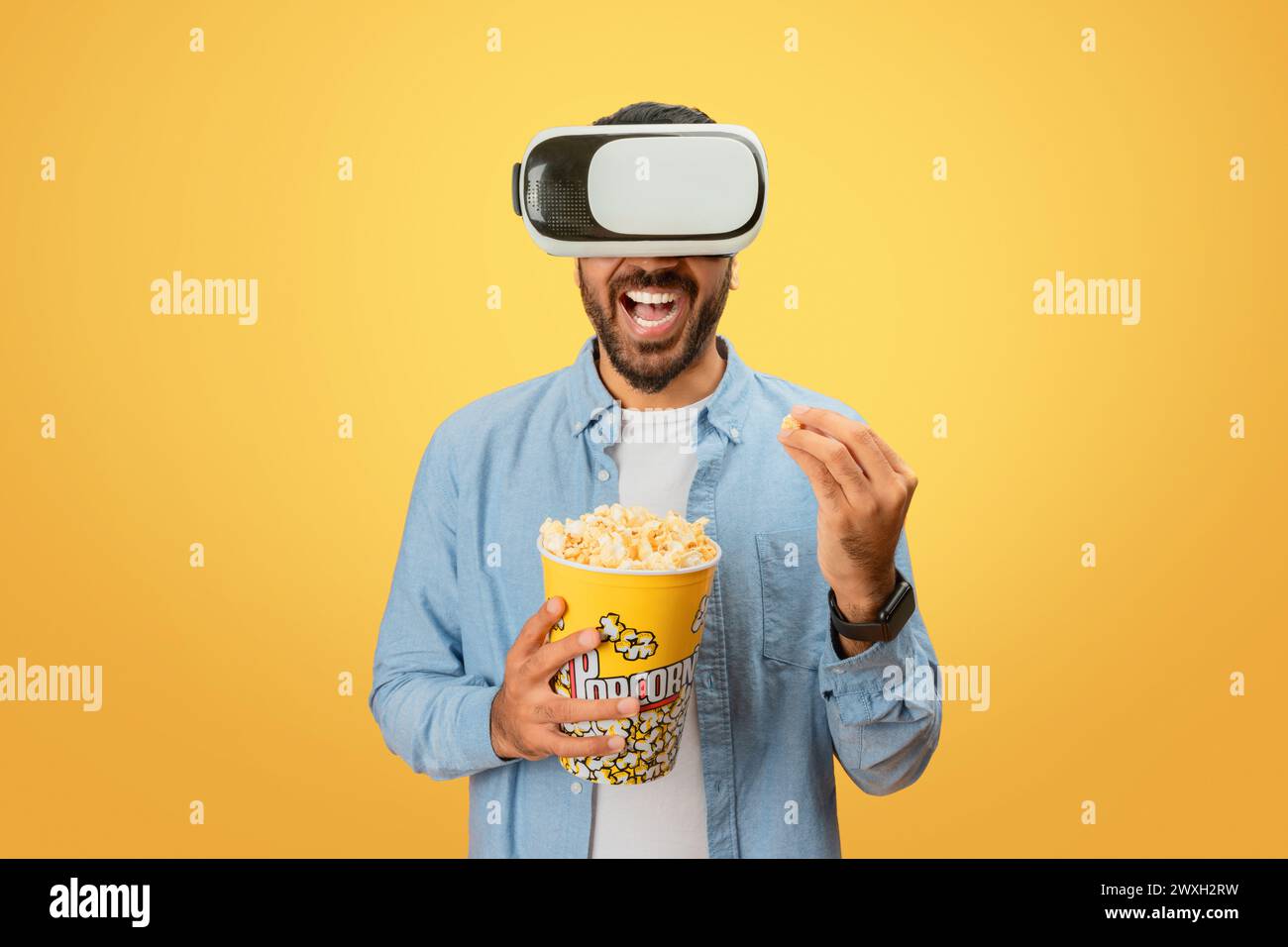 Man eating popcorn experiencing VR technology Stock Photo - Alamy