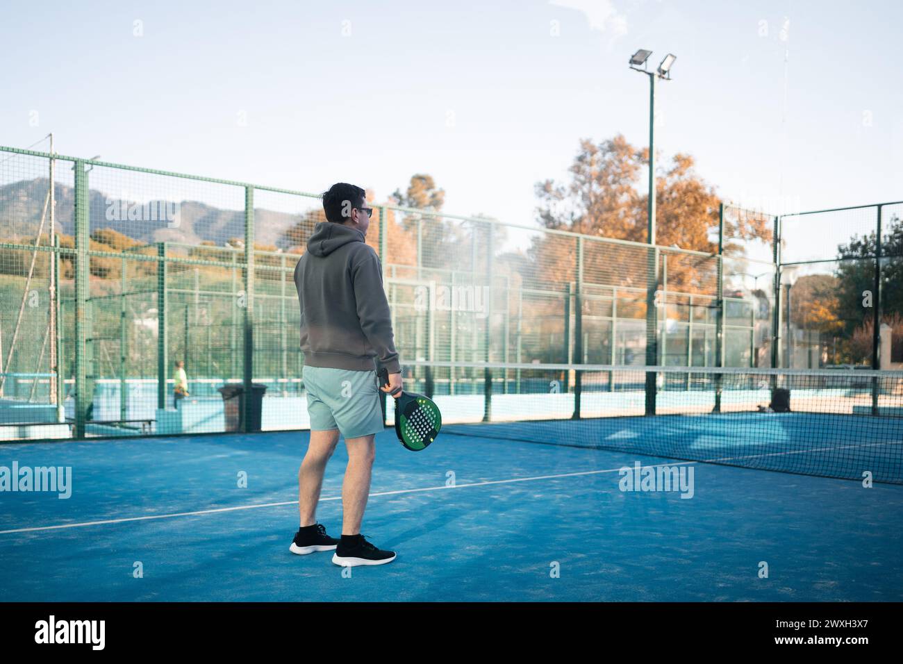 A man prepares for a backhand shot in padel tennis, with a focused ...
