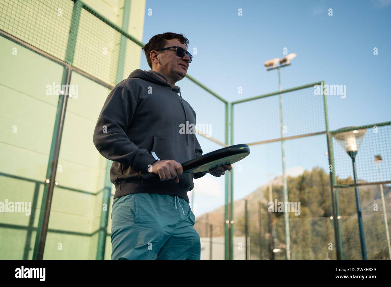 A man prepares for a backhand shot in padel tennis, with a focused ...